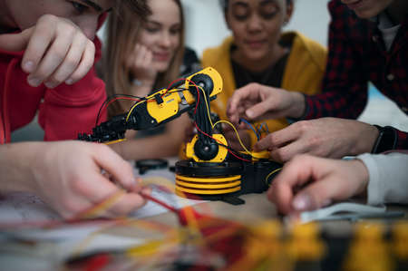 Group of students building and programming electric toys and robots at robotics classroom ...
