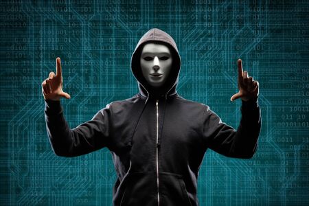 Dangerous hacker over abstract digital background with binary code. Obscured dark face in mask ...