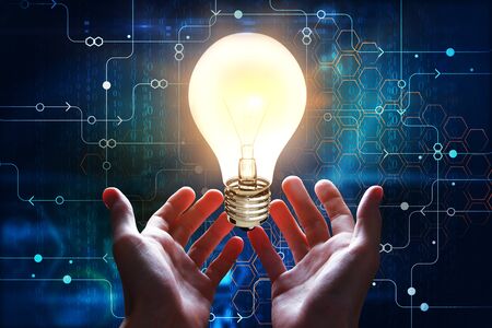Male hands holding abstract glowing light bulb on blue circuit ...