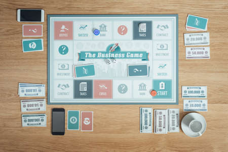 The business board game on a table with pieces, banknotes, cards and ...
