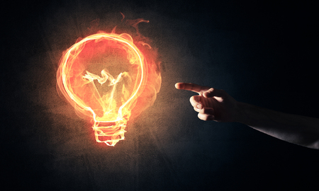 Close of man hand showing at glowing fire light bulb icon - Stock Image ...