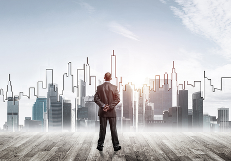 Businessman standing with back and looking at silhouette of modern ...