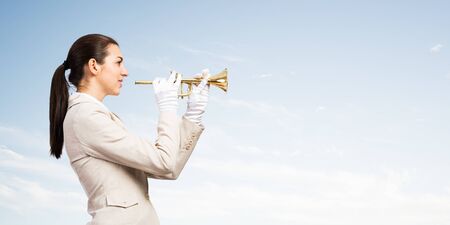 Business woman playing trumpet brass. Young lady in white business suit ...