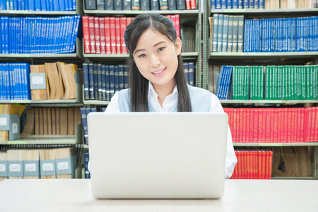 Asian pretty female student using laptop in library - Stock Image ...