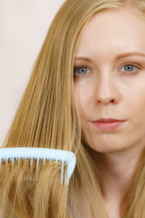 Young woman combing long healthy blonde hair, using comb - Stock Image ...