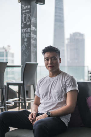 Handsome young Asian man sitting on the rooftop. Chinese guy ...