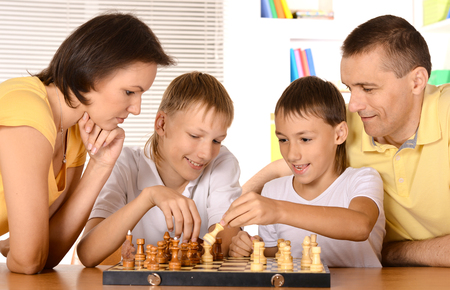Happy family playing chess sitting at table - Stock Image - Everypixel