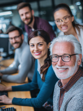 A diverse group of coworkers smiles at the camera while working in a ...