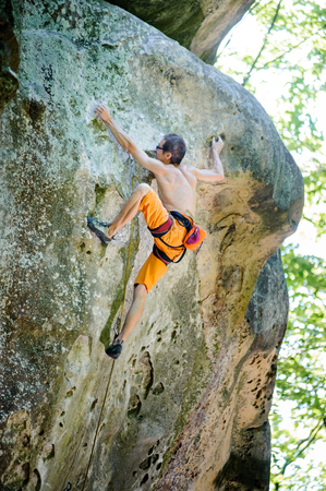 Muscular man lead climbing on a challenging route reaching the top ...