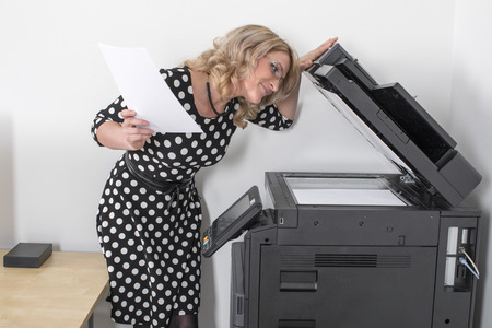 Young beautiful woman in a black polka-dot dress making copies in the ...