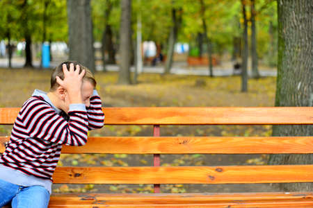 The young guy sits on a bench in park - Stock Image - Everypixel