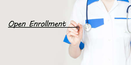 Doctor holding a marker with text OPEN ENROLLMENT medical concept ...