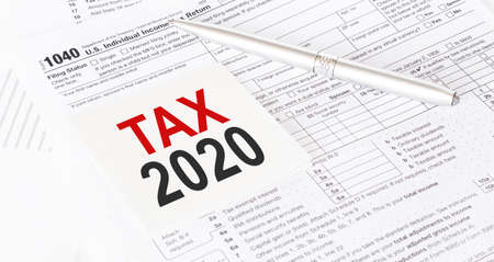 TAX 2020 written on yellow sticker note with paperclip to tax form ...