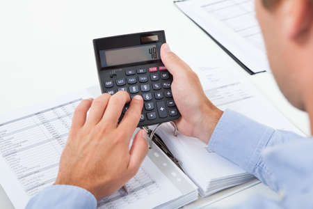 Cropped image of businessman calculating tax at desk in office - Stock ...