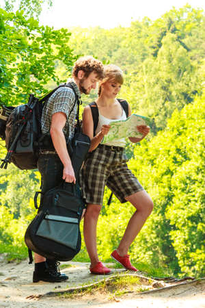 Man and woman tourists backpackers reading map on trip. Young couple ...