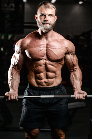 Handsome power athletic man on diet training pumping up muscles with ...