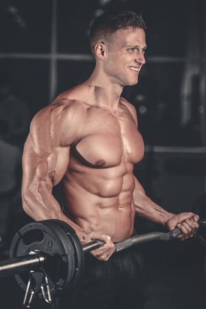 Handsome power athletic man on diet training pumping up muscles with ...