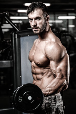 Handsome power athletic man on diet training pumping up muscles with ...