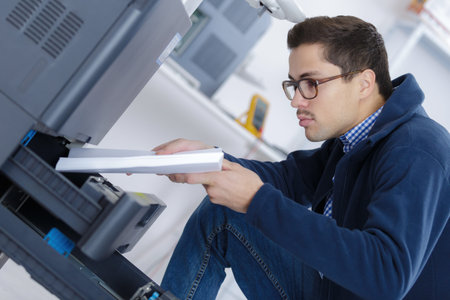 man is putting stack of paper in printing machine - Stock Image ...