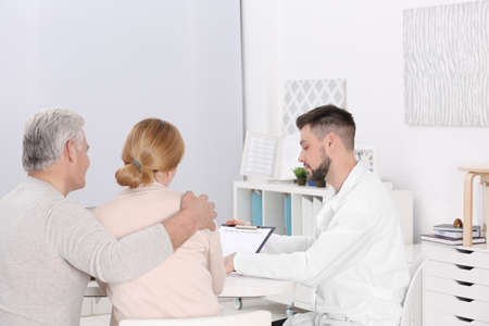 Middle aged couple discussing terms of insurance contract with agent ...