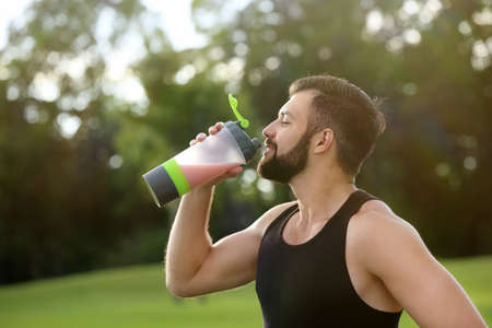 Sporty young man drinking protein shake outdoors - Stock Image - Everypixel