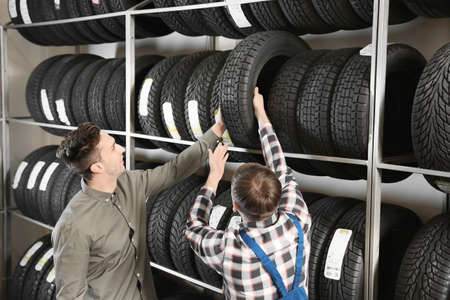 Service center consultant helping customer to choose tire in store ...