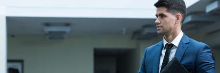 Handsome elegant sales representative in suit waiting for director of ...