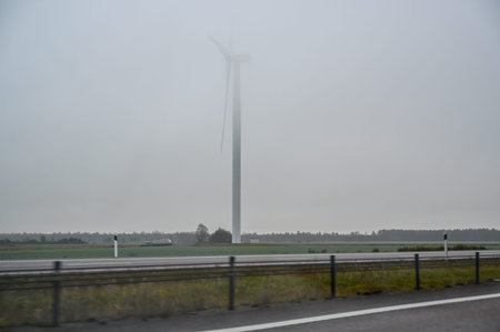 wind power covered in fog near a road - Stock Image - Everypixel
