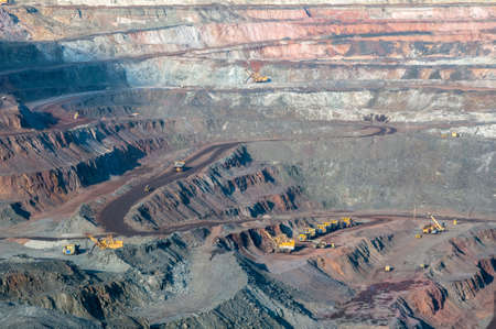 open cast mine extracting iron ore with heavy trucks, excavators ...