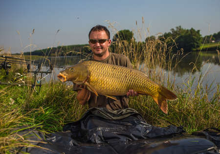 Happy angler with carp fishing trophy - Stock Image - Everypixel