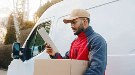 Courier with digital tablet delivering package. Mailman in front the ...