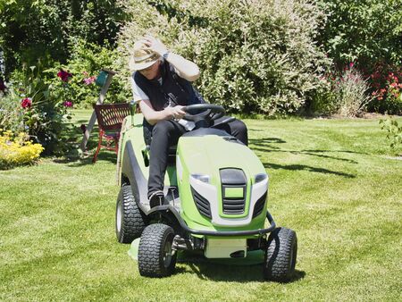 Senior man 75 old years driving a tractor lawn mower in garden with ...