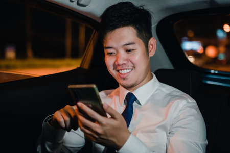 Asian businessman use mobile phone, smart phone after work walking ...