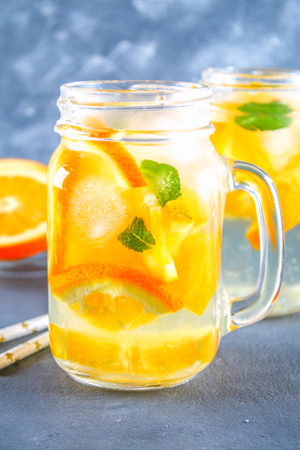 Orange detox water in mason jars on a gray concrete background. Healthy ...