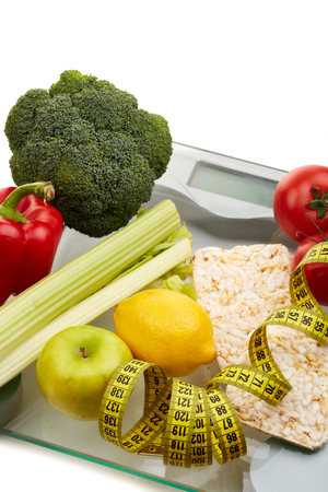 Healthy nutrition. Scales, measuring tape and vegetables on a white ...