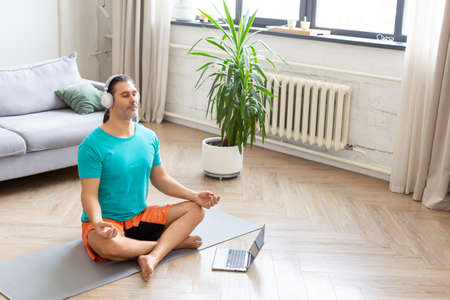 Home workout and healthy lifestyle concept - man meditates at home ...