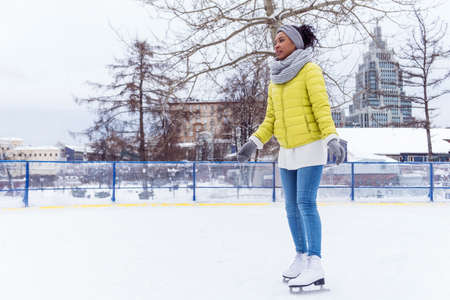 Full lengh portrait of young african american woman skating on ice rink ...