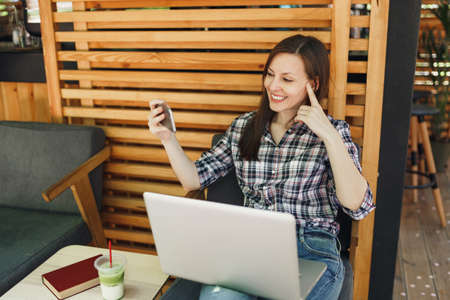 Woman in wooden outdoors street summer coffee shop sitting with laptop ...