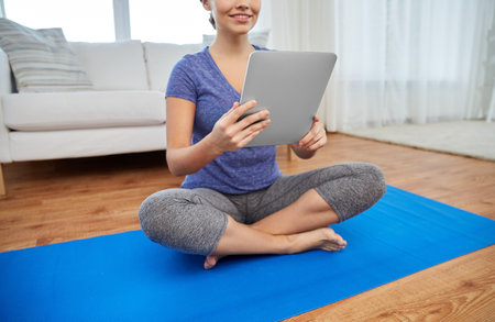 woman with tablet pc computer doing yoga at home - Stock Image - Everypixel