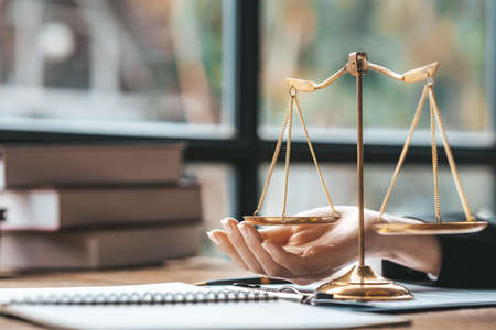 An individual exercises his hand under the scales of justice, lawyers ...