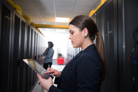 Female IT engineer working on a tablet computer in server room at ...