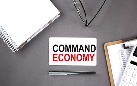 COMMAND ECONOMY Text written on card with notebook and clipboard, gray ...