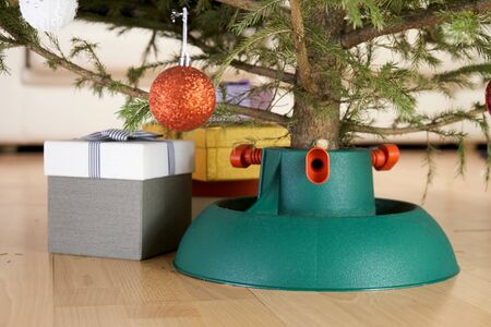 Plastic Christmas tree stand surrounded by gift boxes stands at home in ...