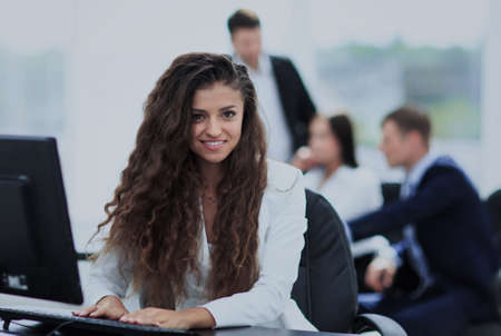 Happy young businesswoman looking behind and her colleagues work ...
