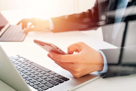 Hands of businessman using mobile phone in modern office with laptop ...