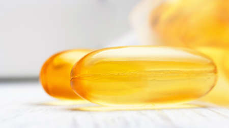 Omega-3 yellow capsules at white wooden planks, nutritional supplements ...
