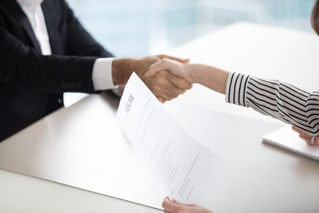Close up of HR manager holding resume shaking hand of male job ...