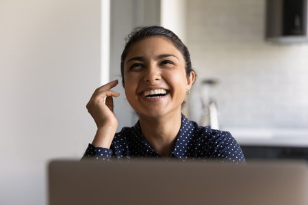 Close up overjoyed Indian woman laughing, using laptop, distracted from ...