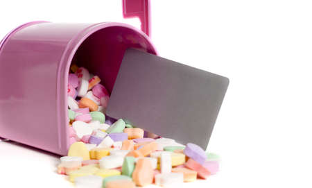 A pink mail box with conversation hearts and a blank notecard fallin ...