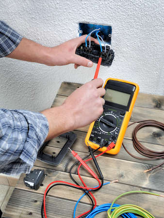 Young electrician at work on switches and sockets of a residential ...